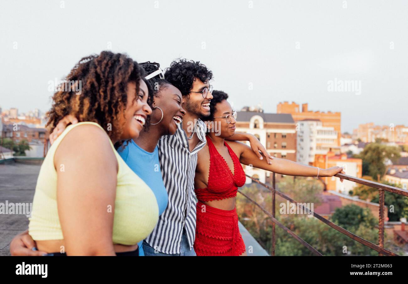 Four cheerful multiethnic friends look at city landscape. Cute African ...