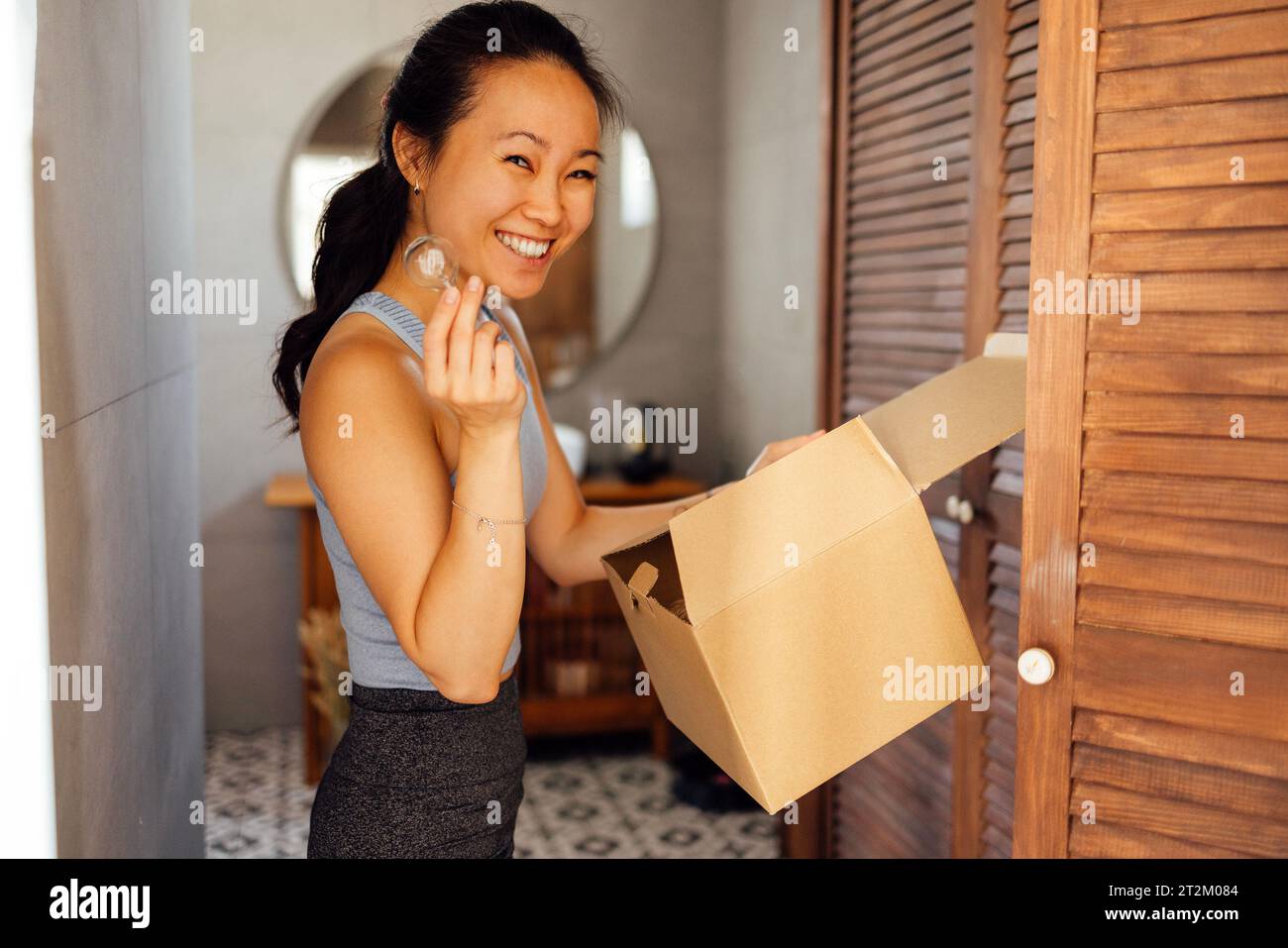 Pretty young Asian woman holds light bulb and cardboard box near ...