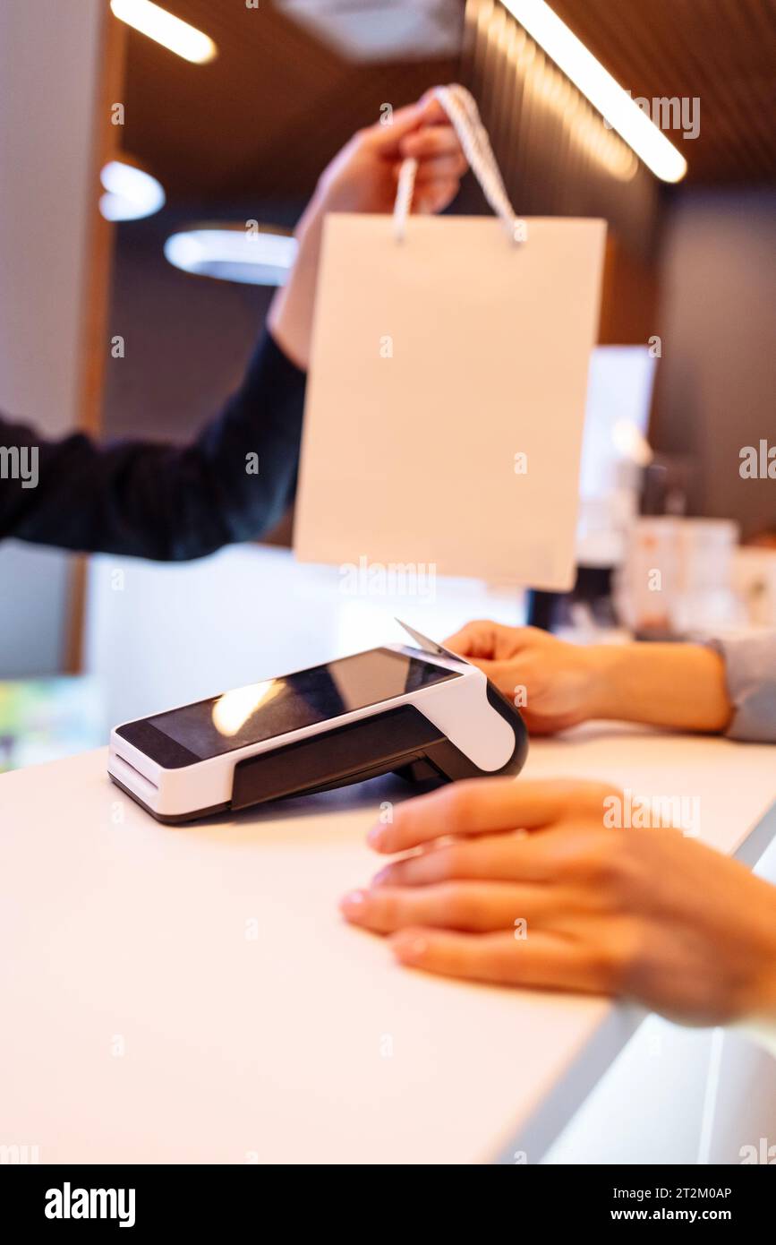 Woman at counter paying with credit card through contactless NFC ...