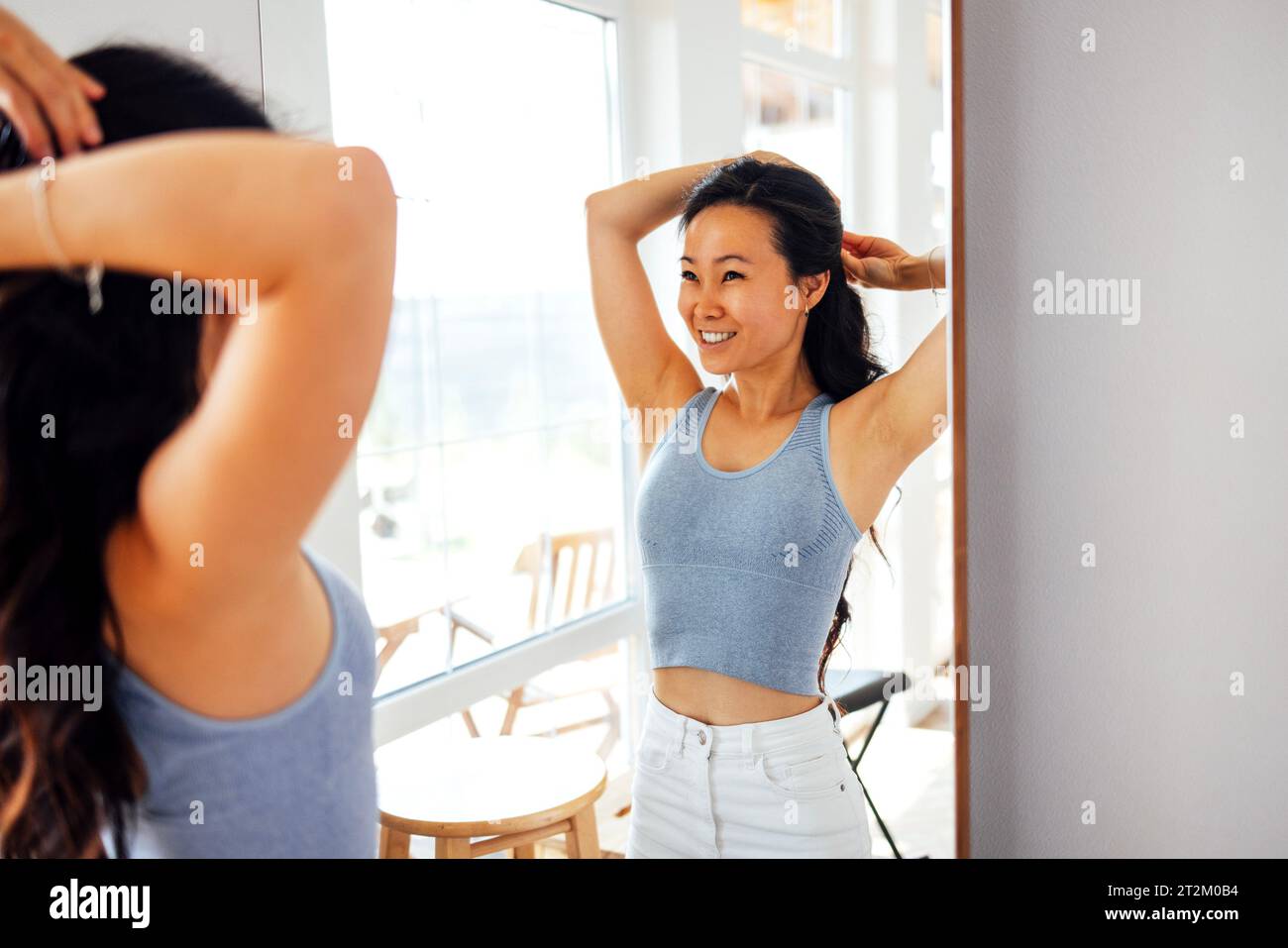 A young attractive Asian woman in casual clothes combs in front of the ...