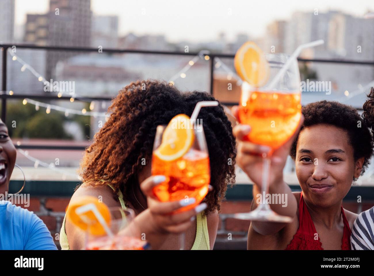 Company of four cheerful friends are enjoying tasty cocktails. Roof ...