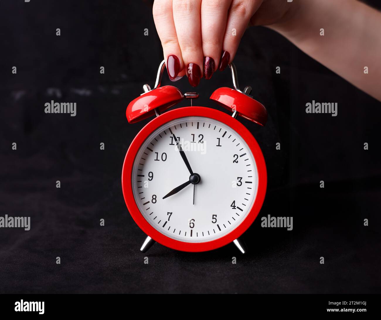 Female arm hold up red alarm clock Stock Photo - Alamy