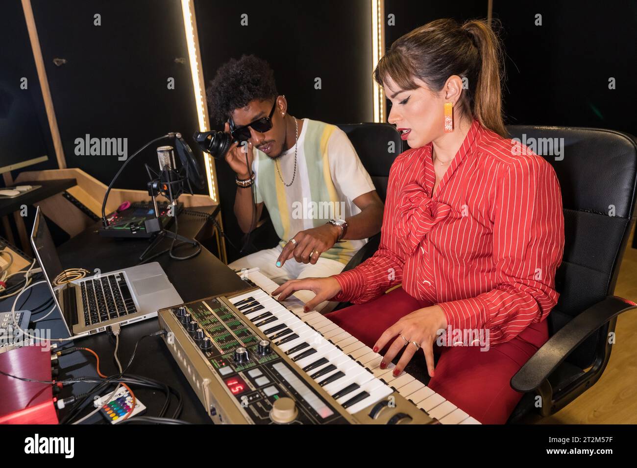Pianist recording a new song in a studio with the help of a technician ...