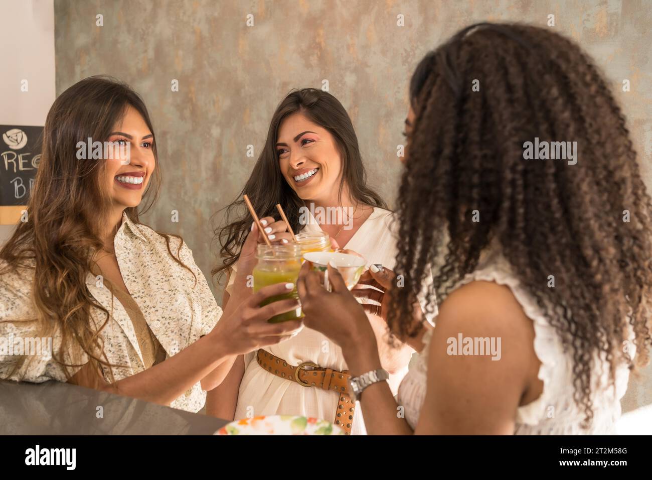 Three latin happy women toasting with juices in a cafeteria Stock Photo ...