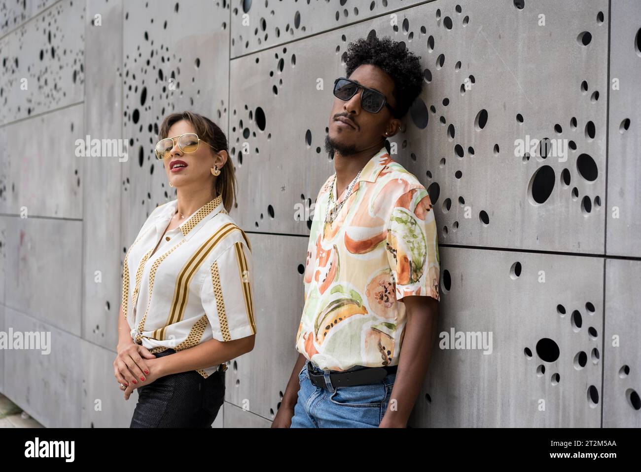 Side view portrait of two multiracial and modern stylish friends posing together in an urban ...