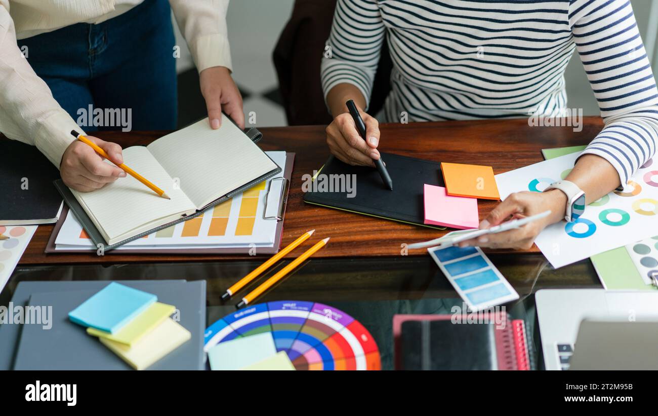 Two creative graphic designers hold color swatches to discussing and ...