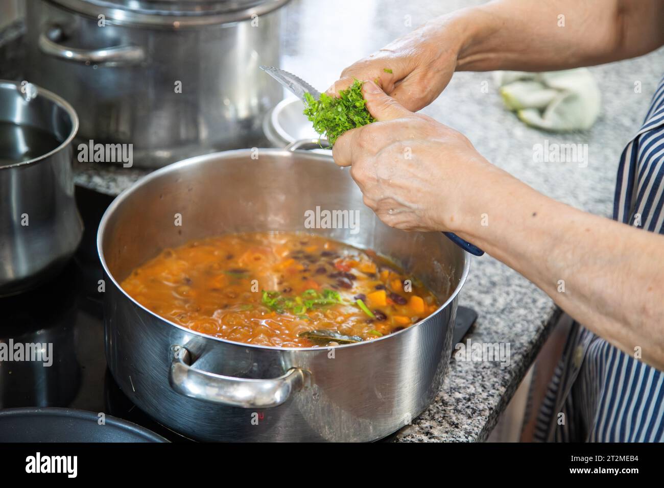 Detail of a person cooking food on the electric hob with pans and ...
