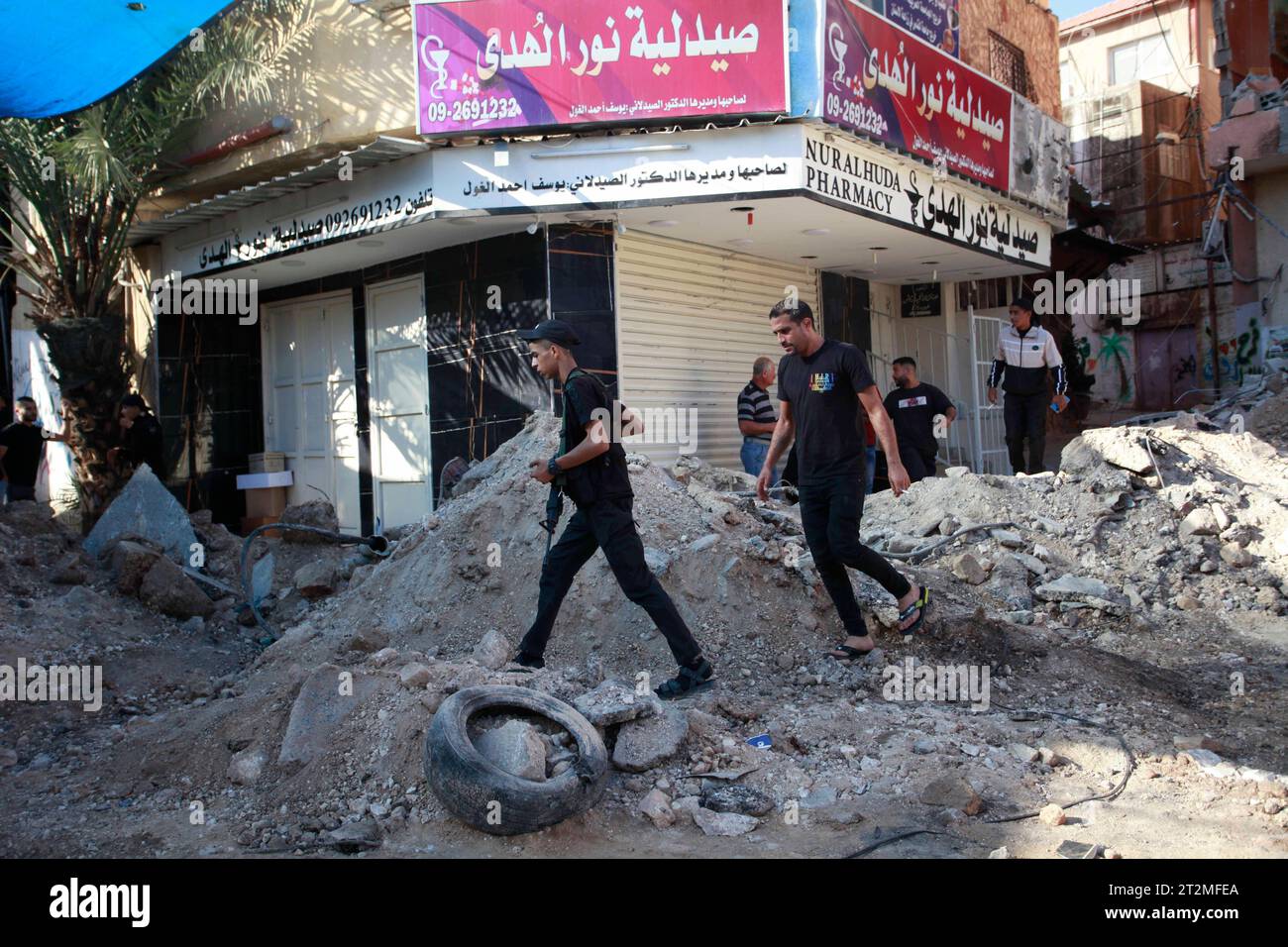 Palestinians walk next to a building damaged during a raid by Israeli ...