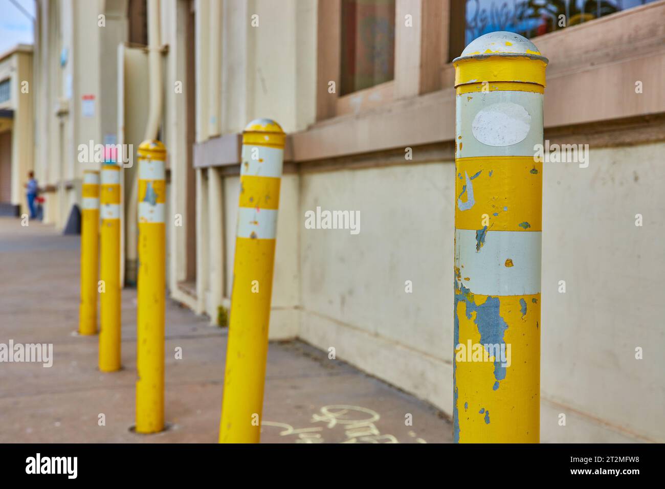 5 yellow poles with white stripes on top and chipping paint lined up on ...