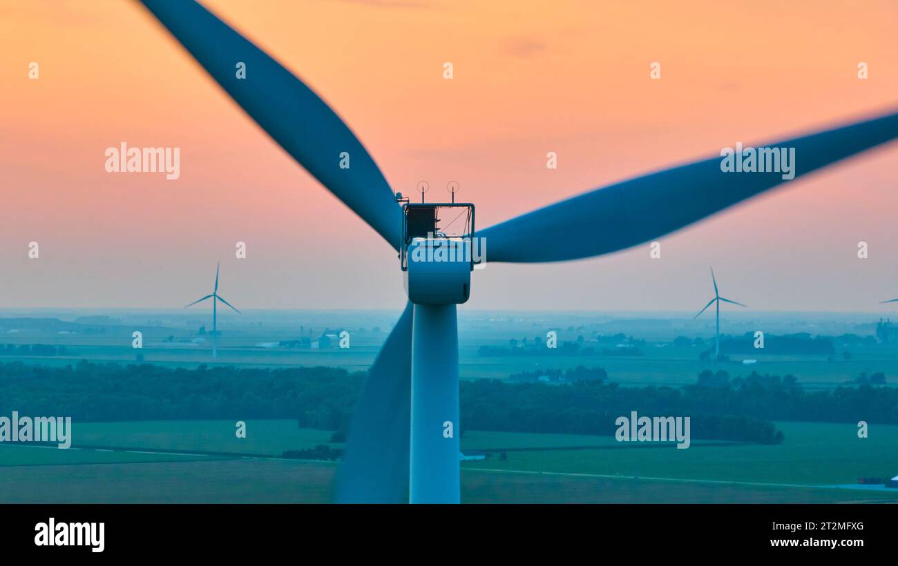 Aerial straight of back of wind turbine with distant turbines in green ...