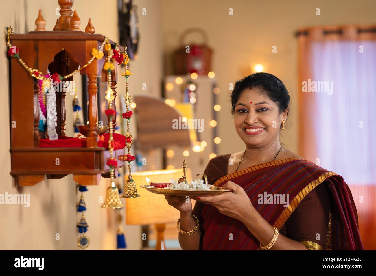 Indian woman Looking camera after offering arthi or puja to god at home ...