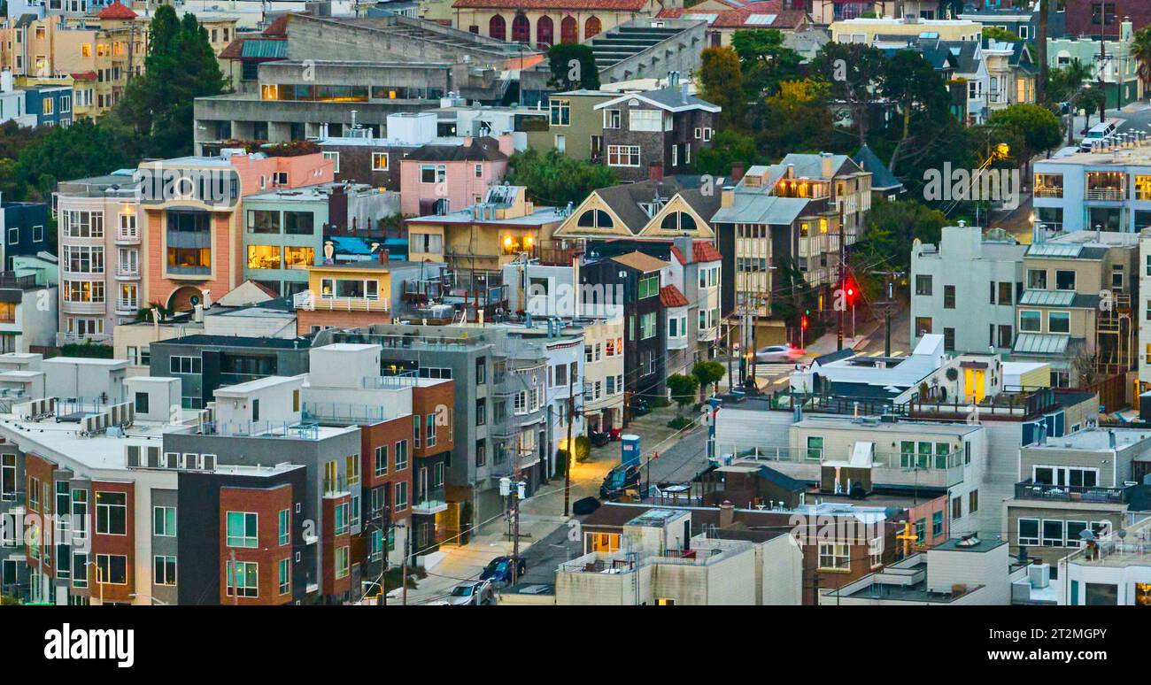 Aerial city street at dusk with lights on in buildings and along road ...
