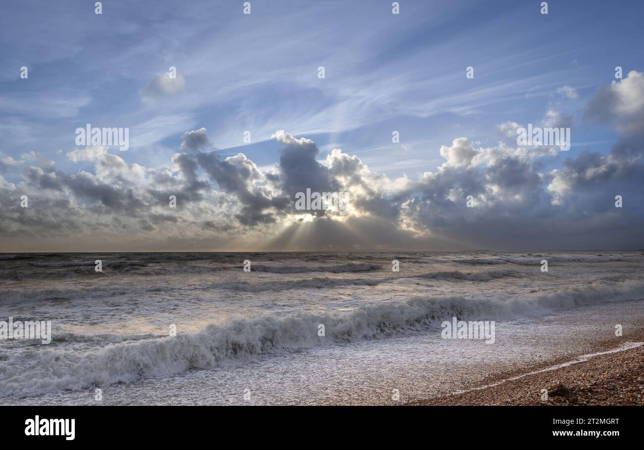 Stormy sunset over the ocean with blue sky, white rolling waves and ...