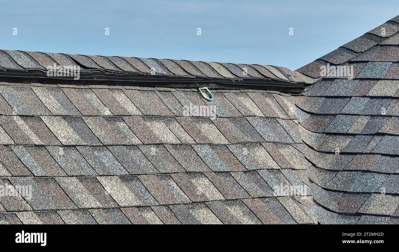 Close up aerial of gray and brown shingles with focus on roof anchor ...