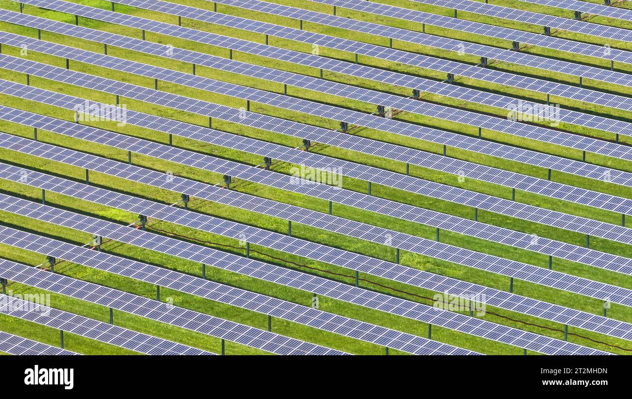 Tilted solar panels on solar farm in grassy field aerial background ...