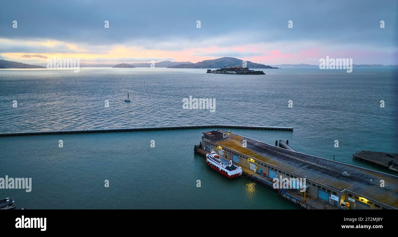 Ship at edge of pier with Alcatraz Island having pink and golden glow ...