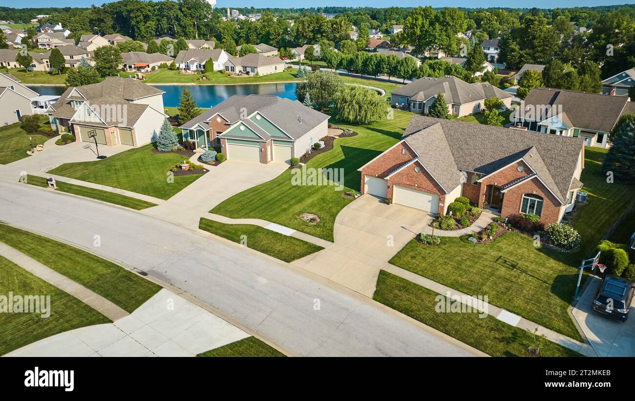 Aerial over a few houses with clean street and driveway and distant ...