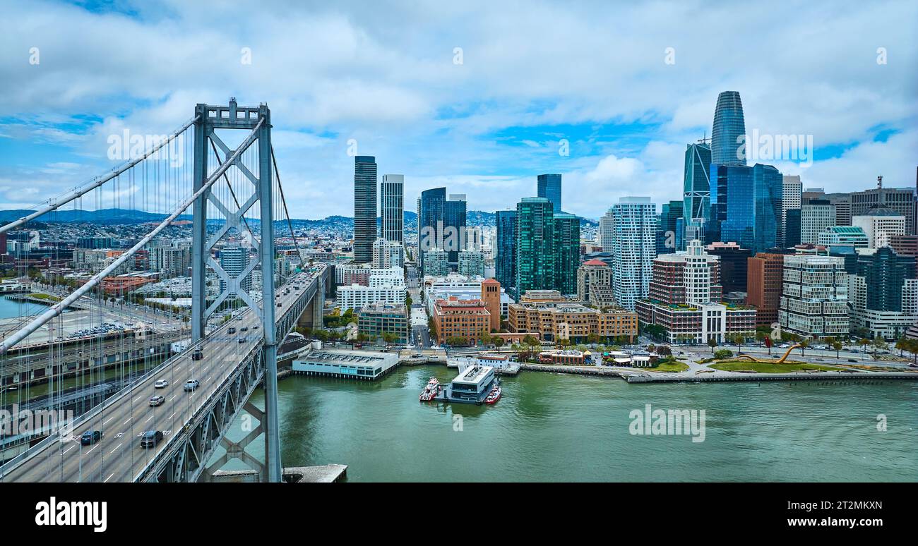 Aerial Oakland Bay Bridge going into city on cloudy blue sky day with ...