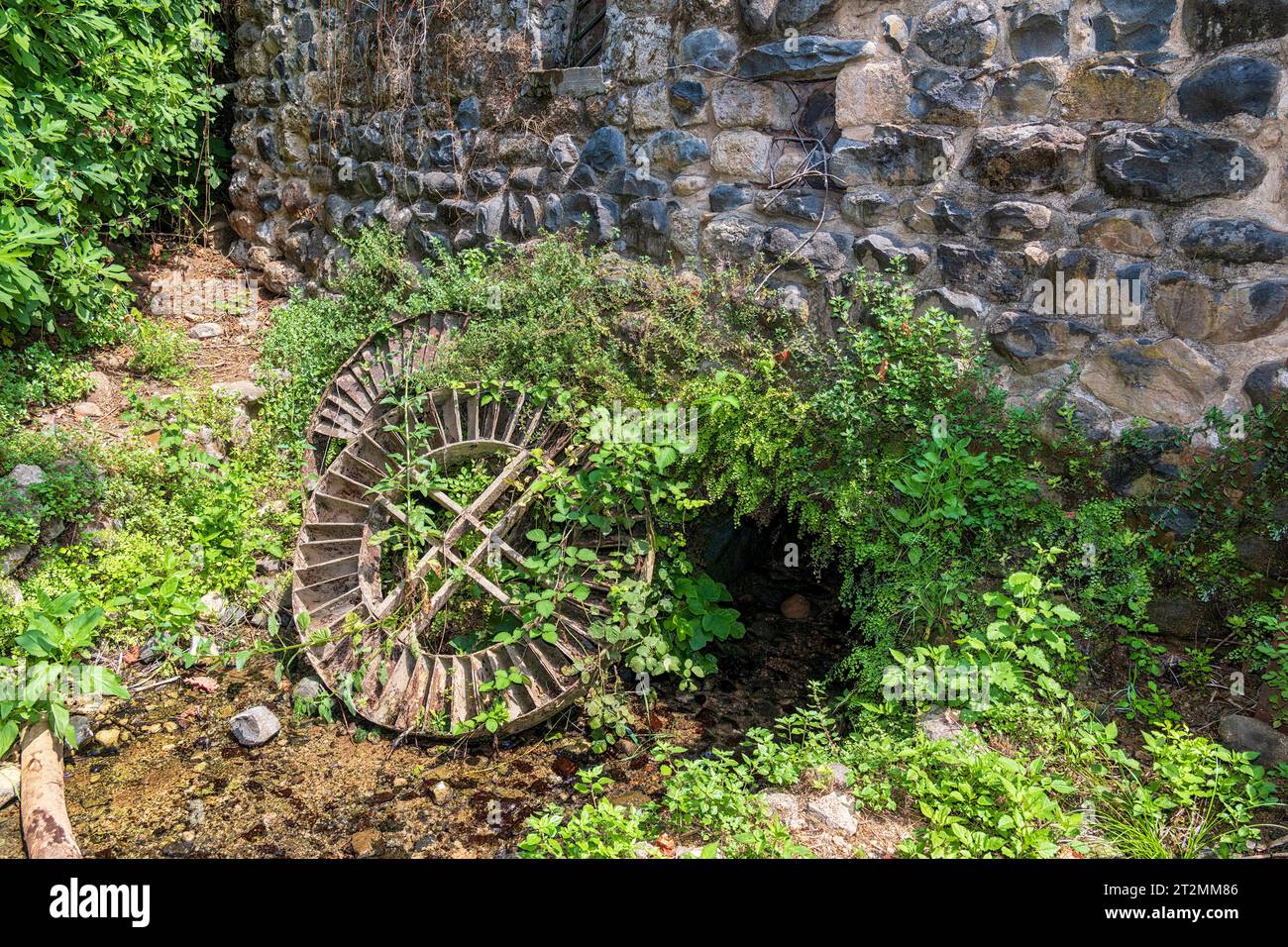 Old metal waterwheels near the ancient building of an old flour mill at ...