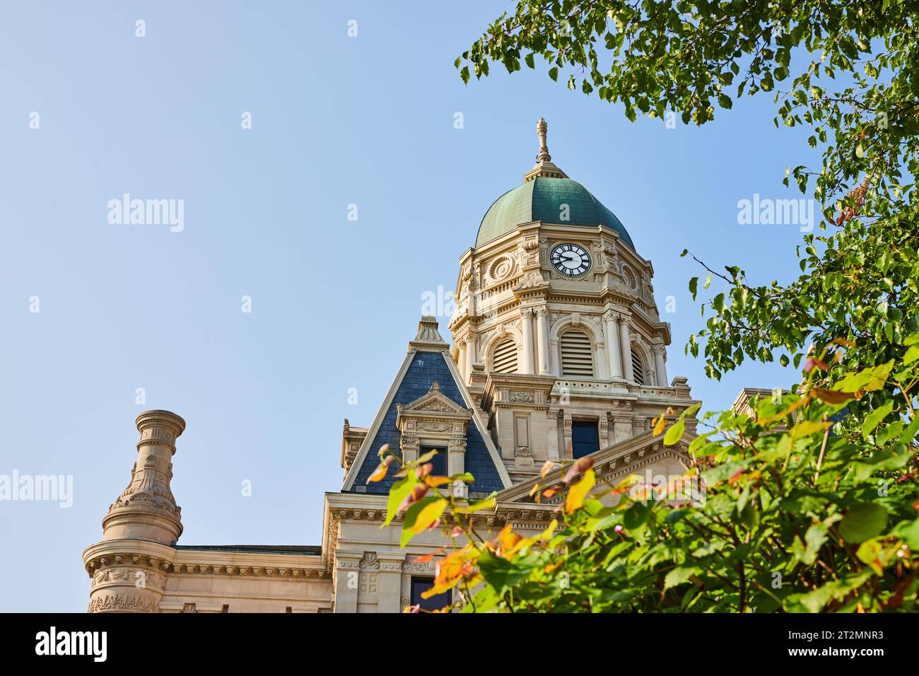 Nine forty on clock face of tall courthouse building with by tree ...