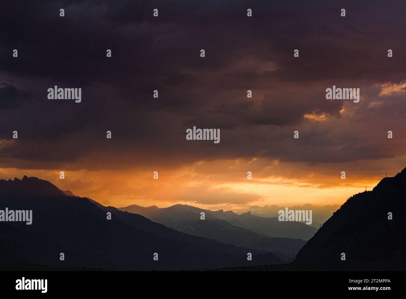 Summer landscape view of the sun rising through the dark clouds above ...