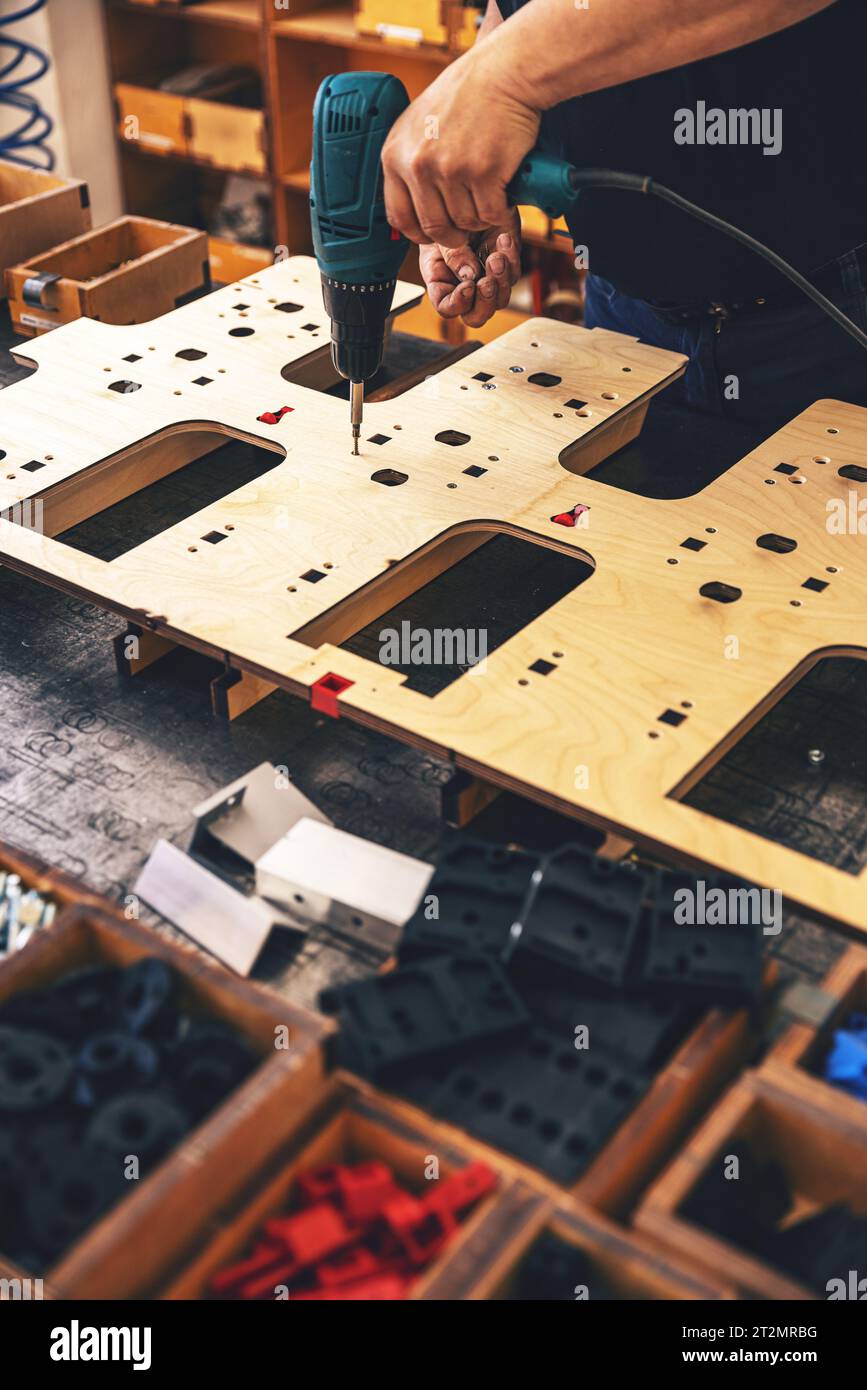 Worker's hands on a workbench with different tools using a screwdriver ...