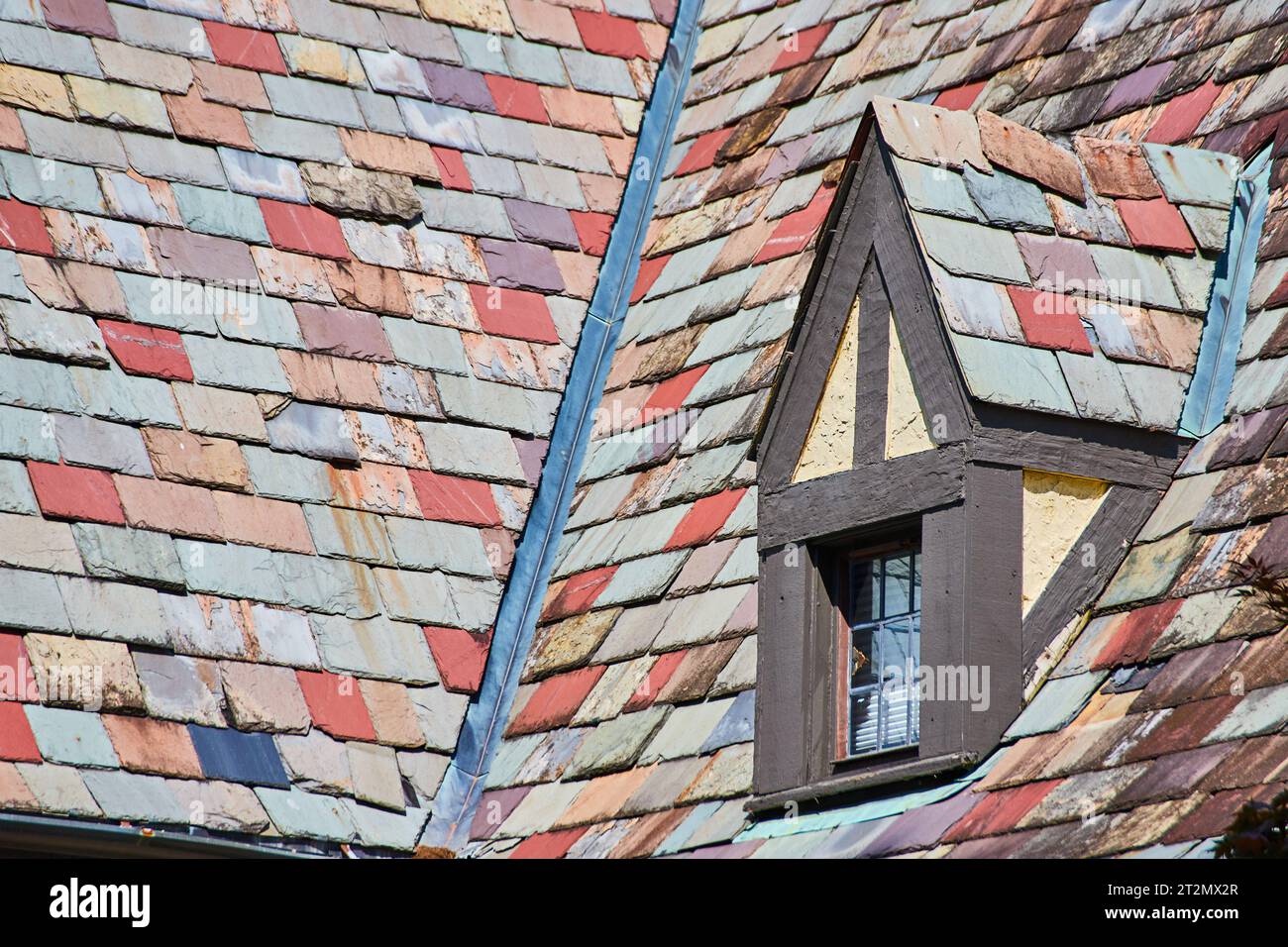 Varying red and blue tiles on roof with tiny triangle shaped roof over ...