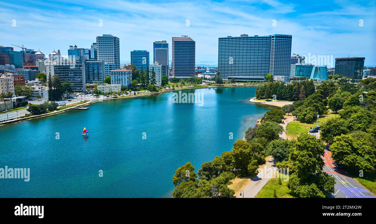 Lone sailboat on Lake Merritt with aerial of downtown Oakland buildings ...