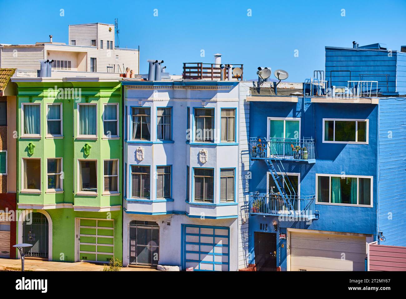 Three houses in compact row with clear blue sky overhead in California ...
