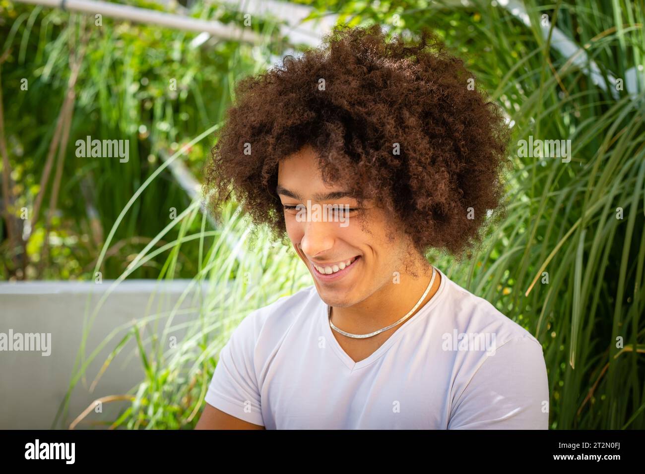 Portrait of a laughing handsome young ethnic boy with curly hair in a ...