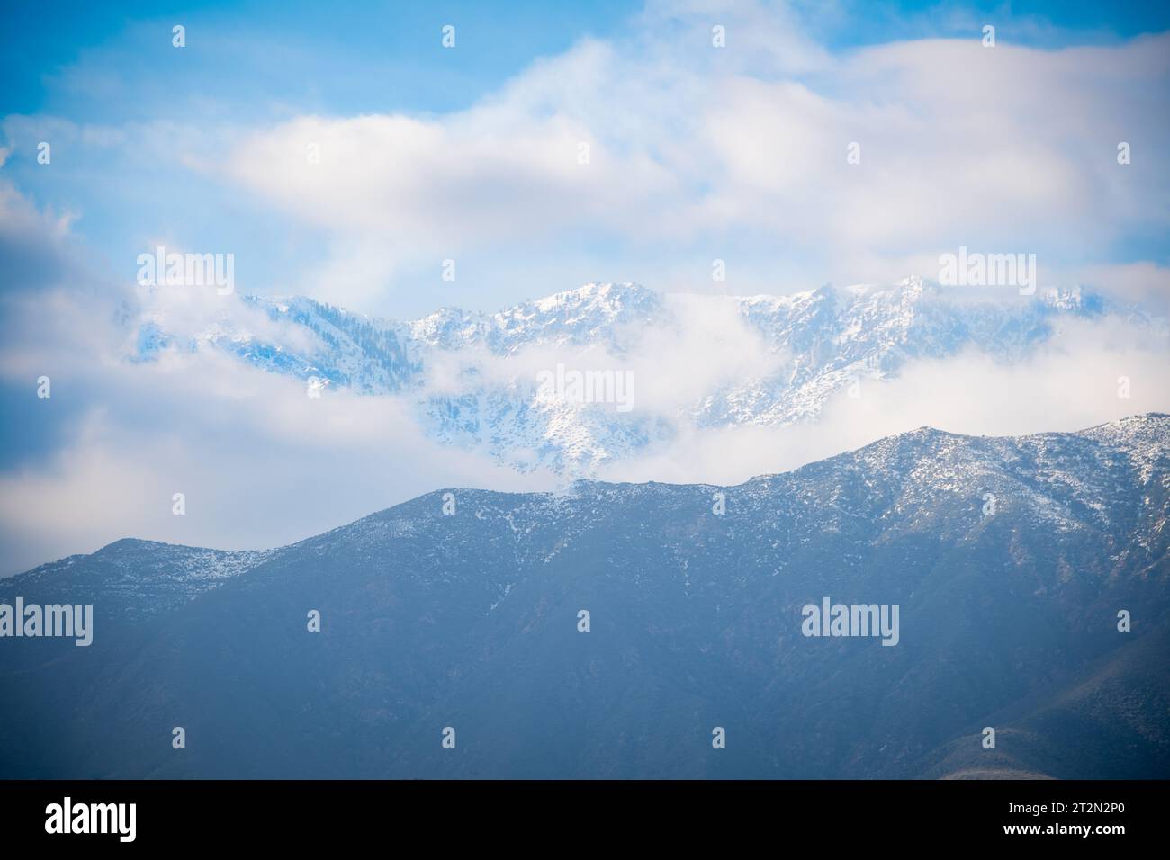 Foreground green foothills, snow-capped mountain peaks and wintry ...