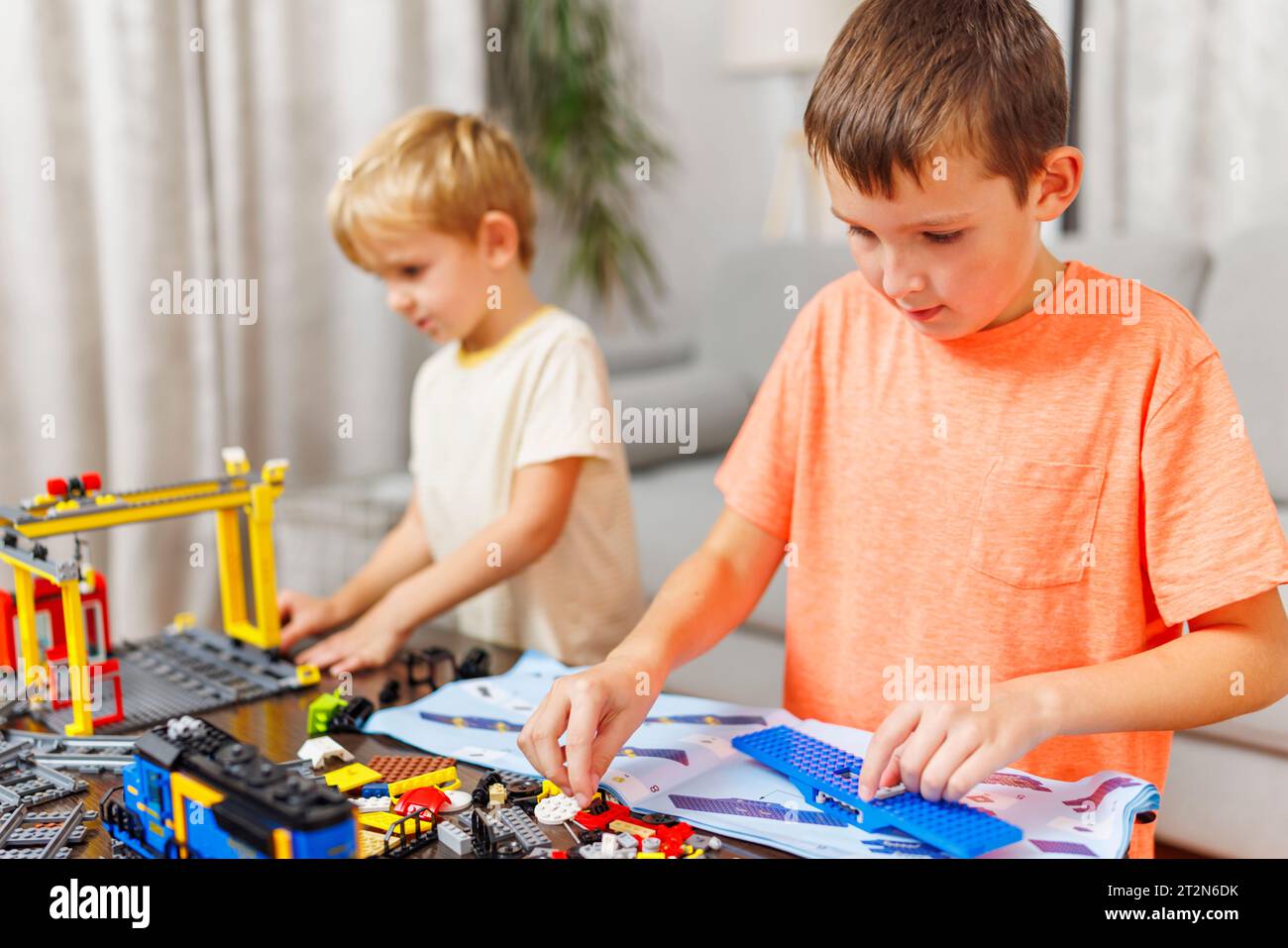 Two children playing and building with colorful plastic bricks at the ...