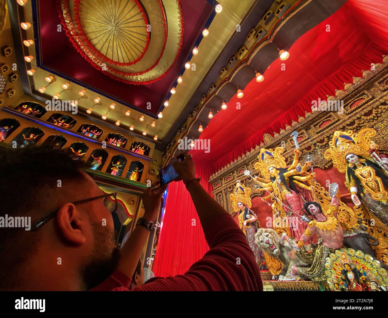 A visitor takes photos of an idol of the Hindu Goddess Durga at the ...