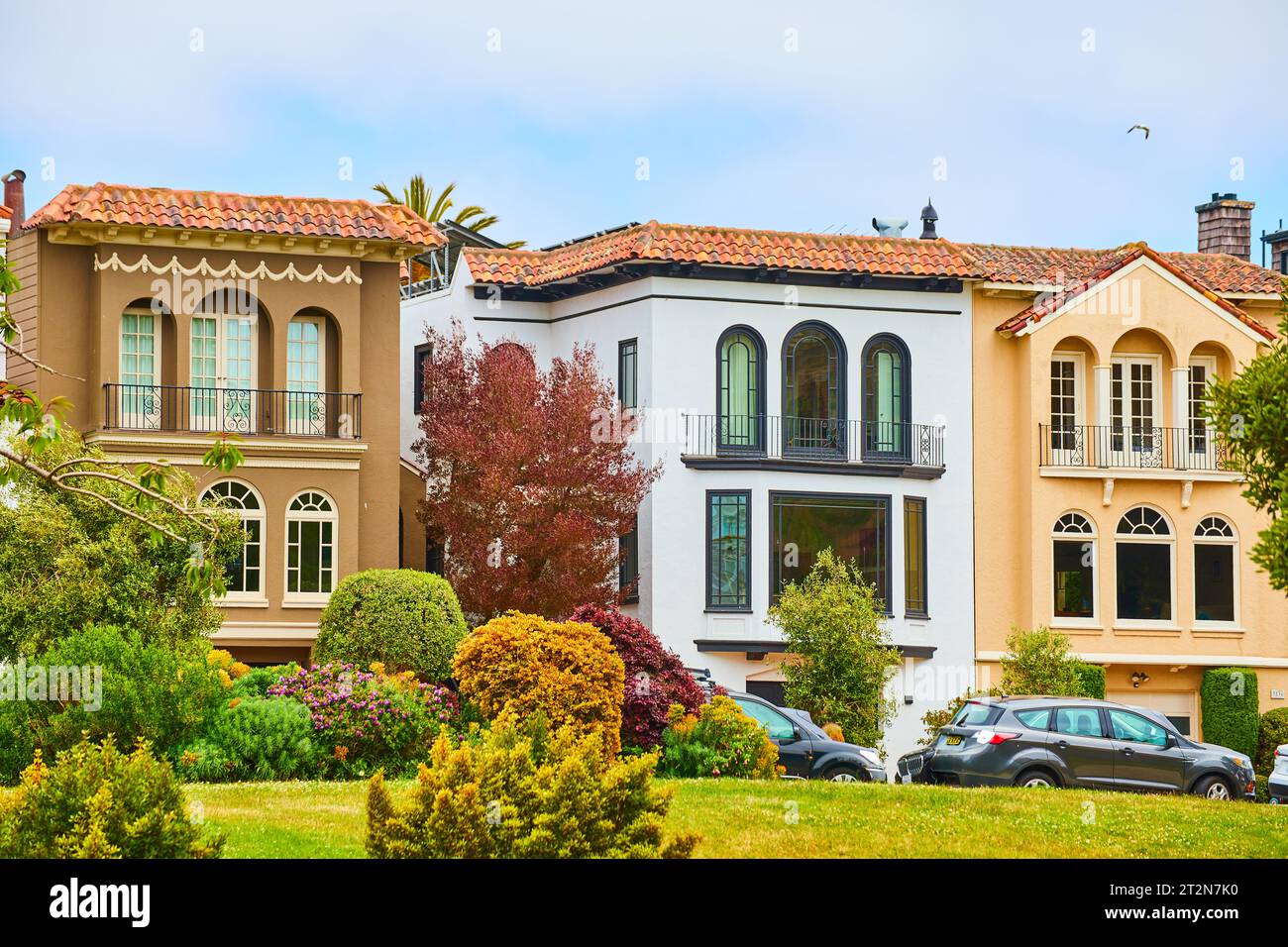 Three houses with large windows and balconies out front with green ...