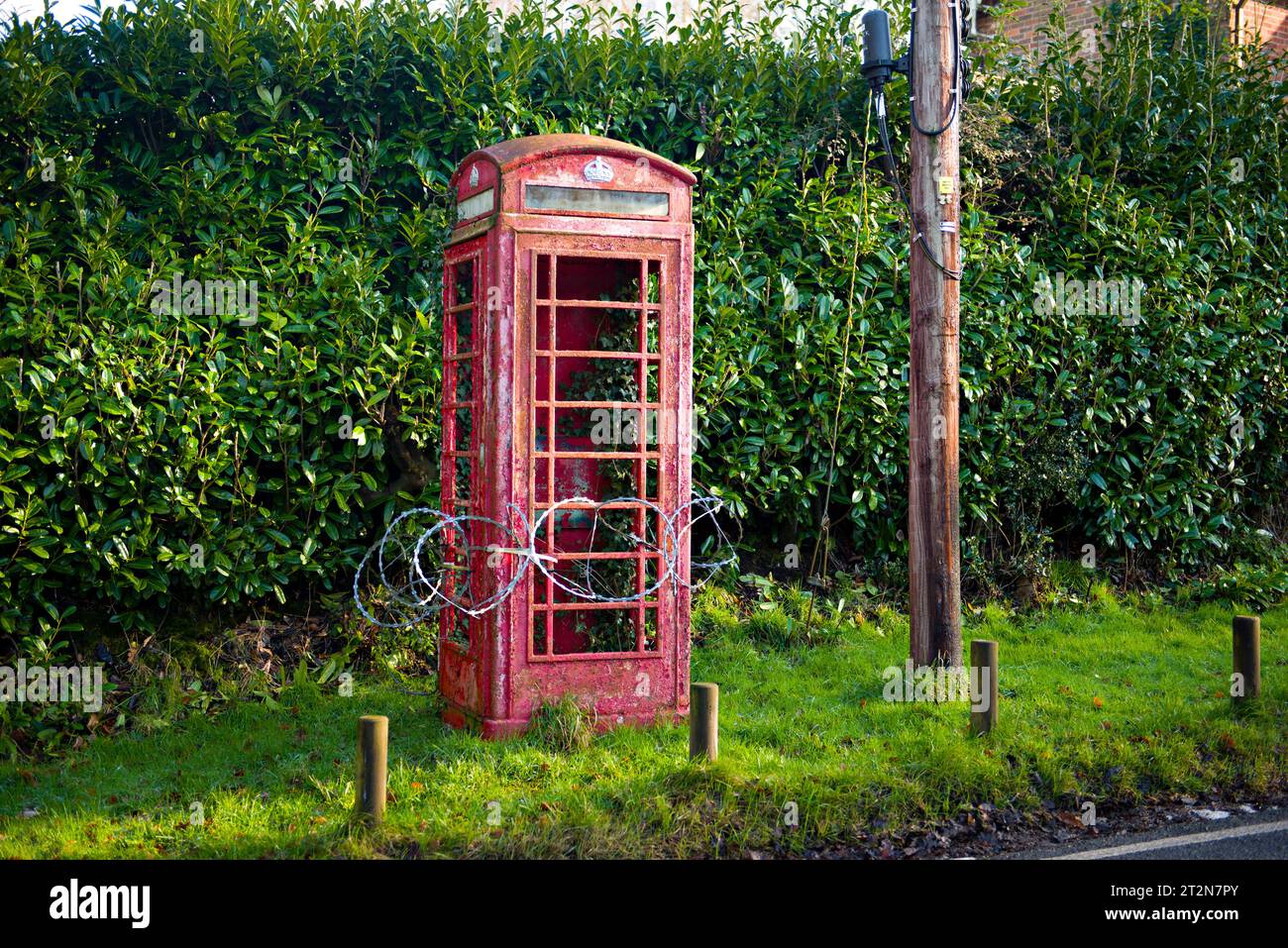 A decommissioned K6 telephone box surrounded by razor wire on a rural ...