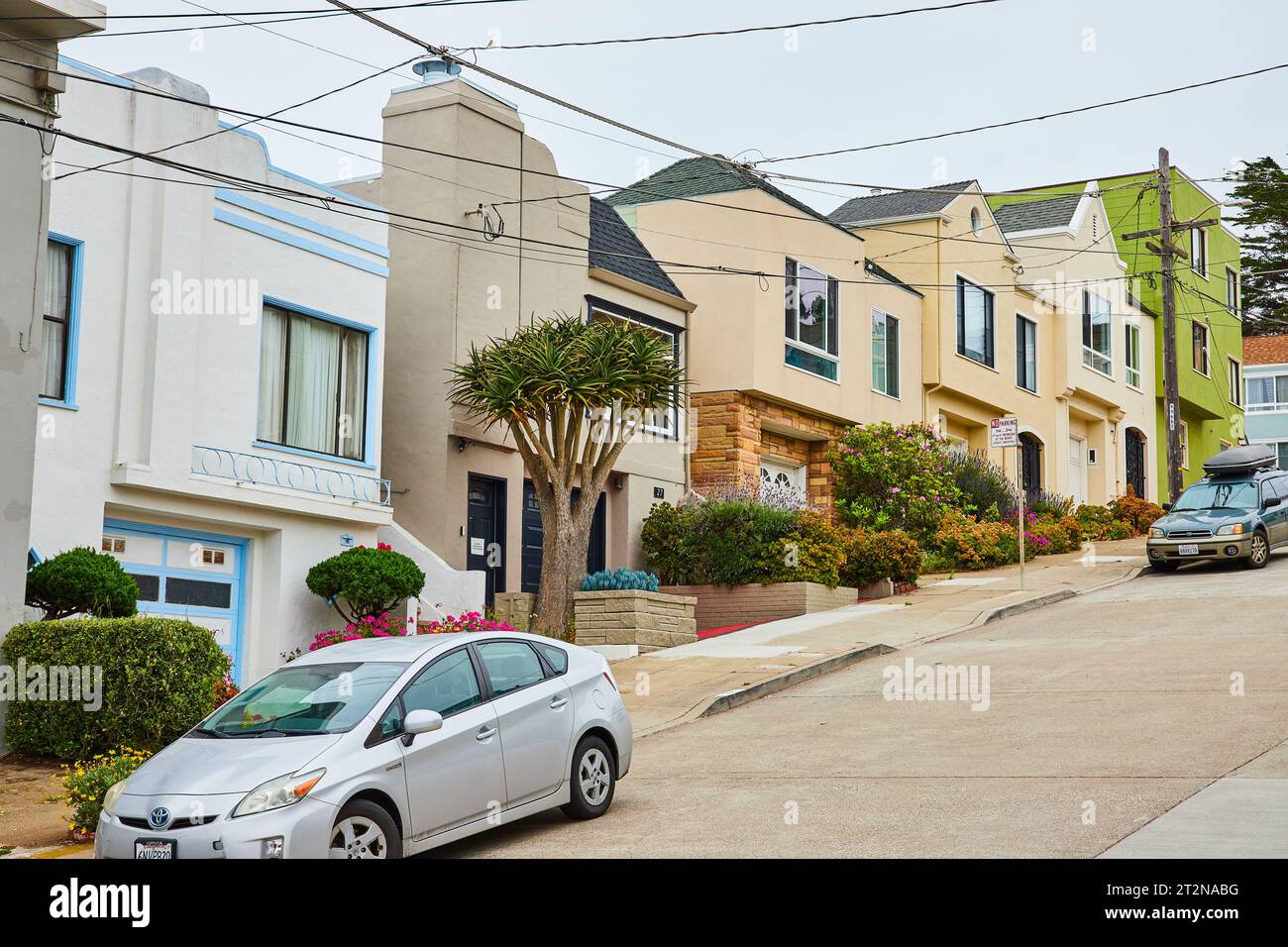 Row of houses beside street going uphill side by side with wires ...