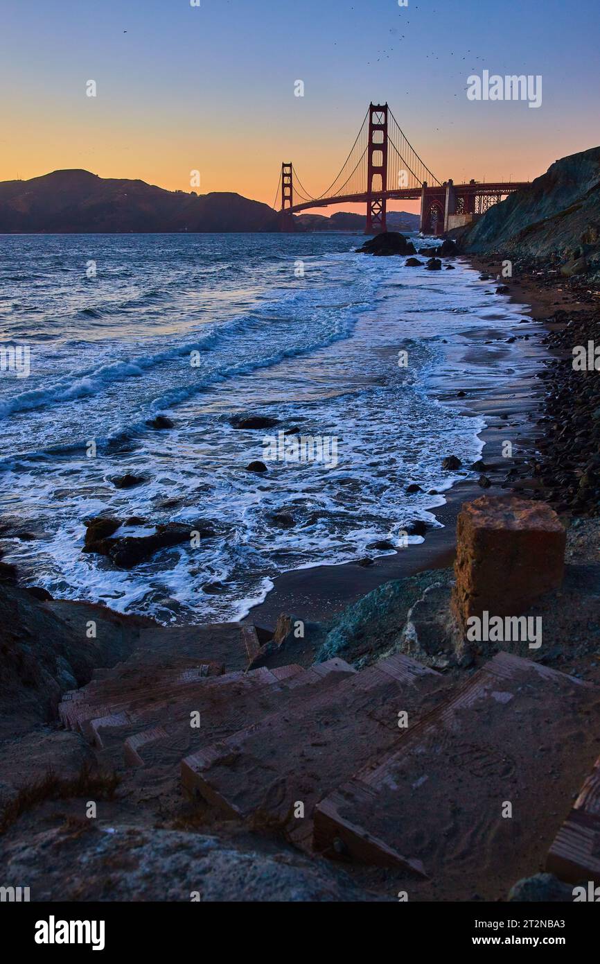 Stairs going downhill to beach with glowing blue waves and sunset sky ...