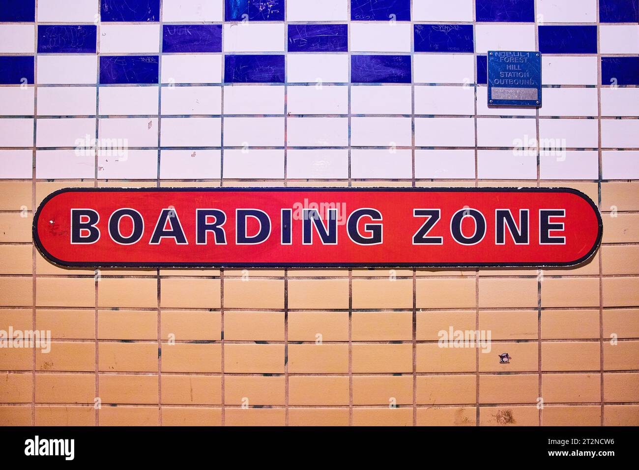 BOARDING ZONE in black and red on tile wall split between tan and white ...
