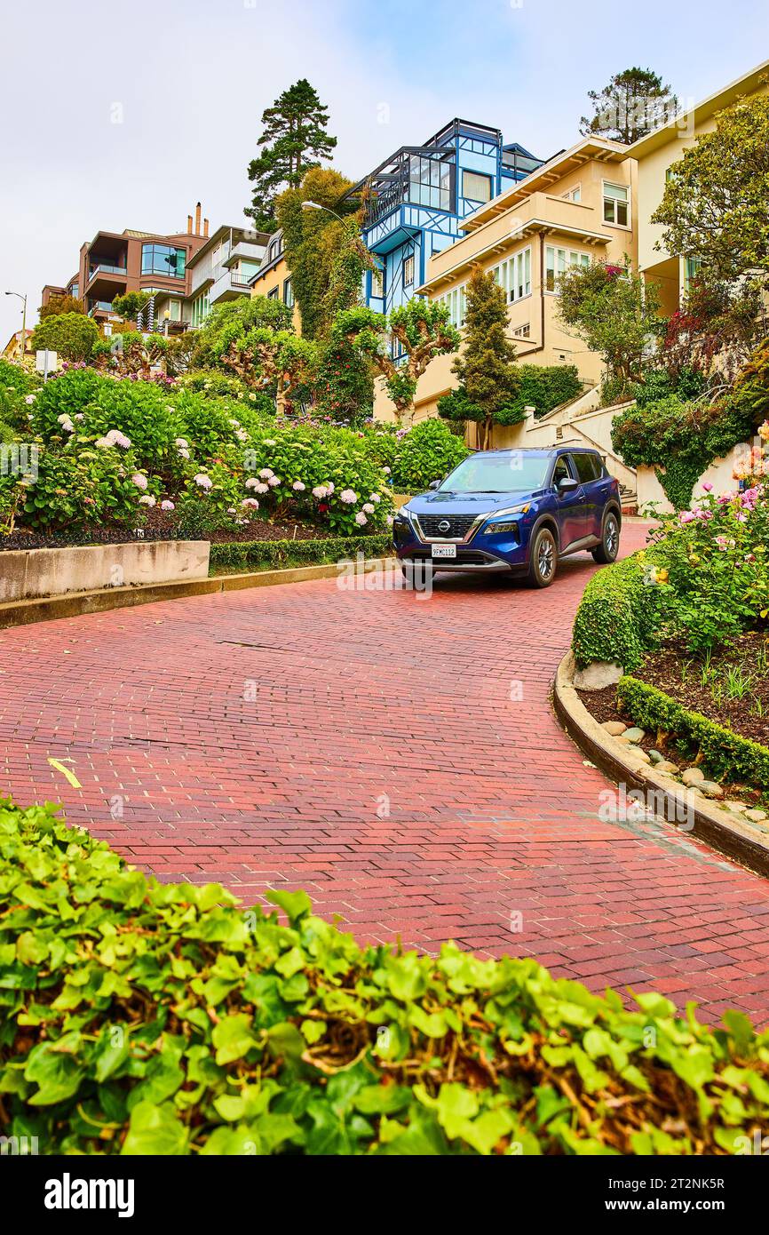 Red brick road with blue vehicle going down Lombard Street Stock Photo ...
