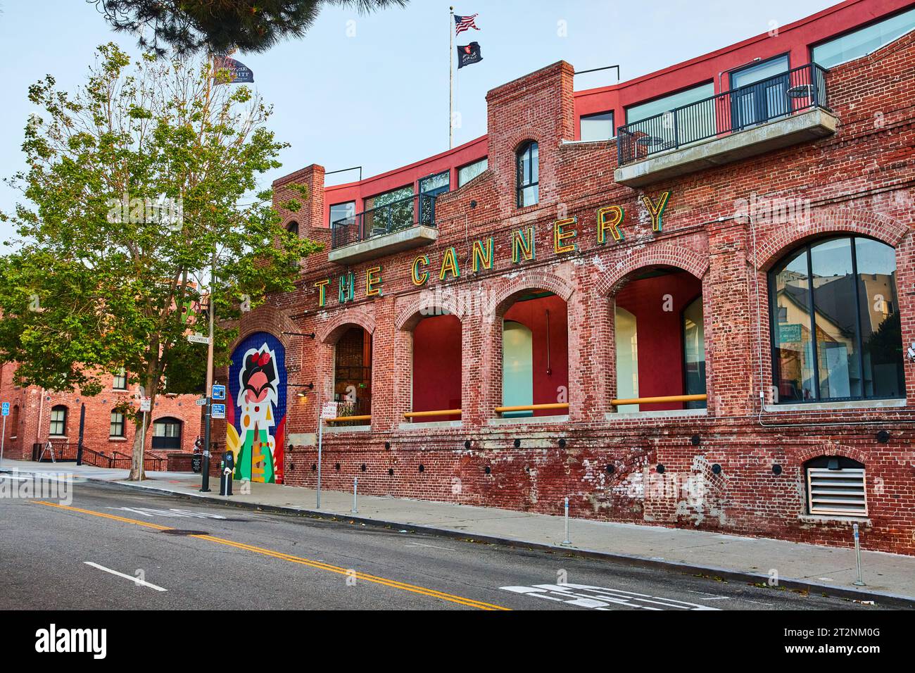 The Cannery fading red brick building with wall mural art on blue sky ...