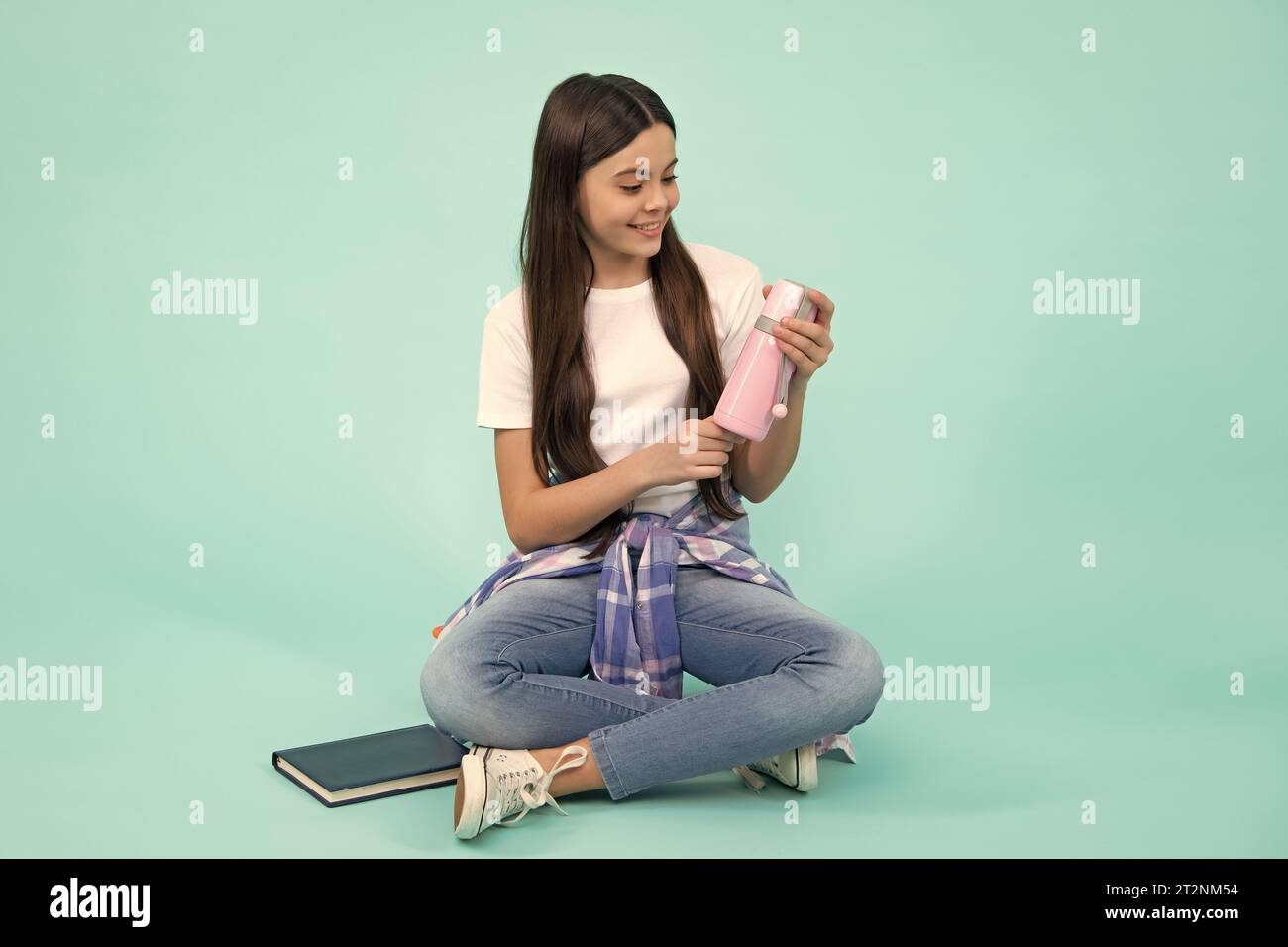 12, 13, 14 year old girl holds thermos and mug of hot tea. Happy ...