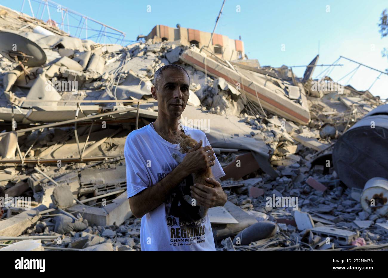Gaza. 20th Oct, 2023. A man holding a cat stands among the rubble of a ...