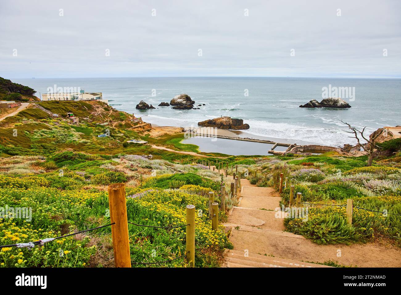 Wide view of sandy trail with stairs leading down to ocean with ...
