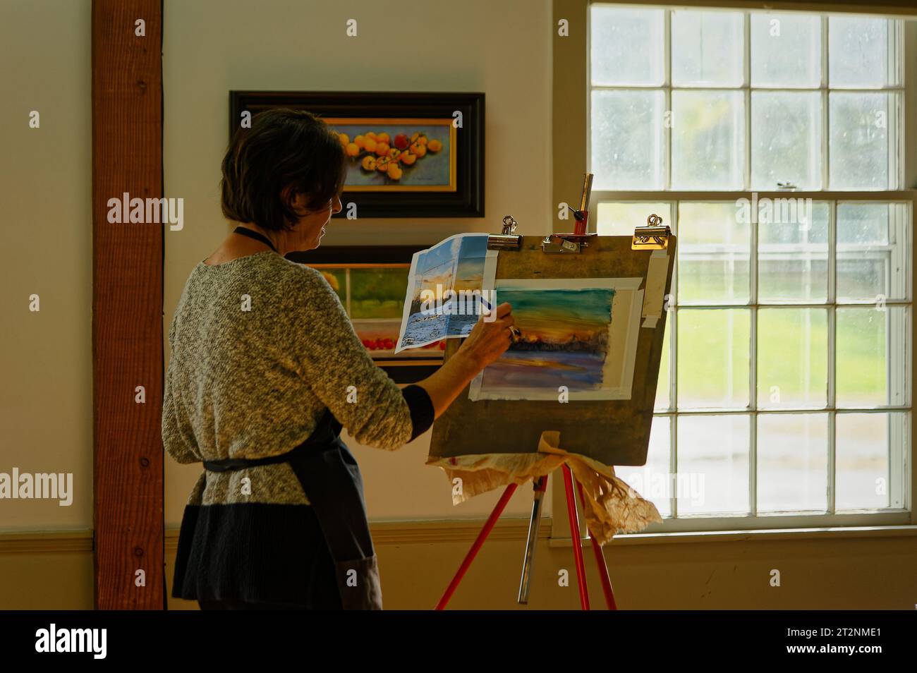 An art instructor gives lessons on painting a sunset with pastels to an ...