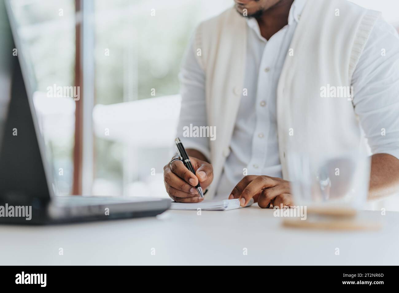 Young black businessman taking notes during presentation and writing ...