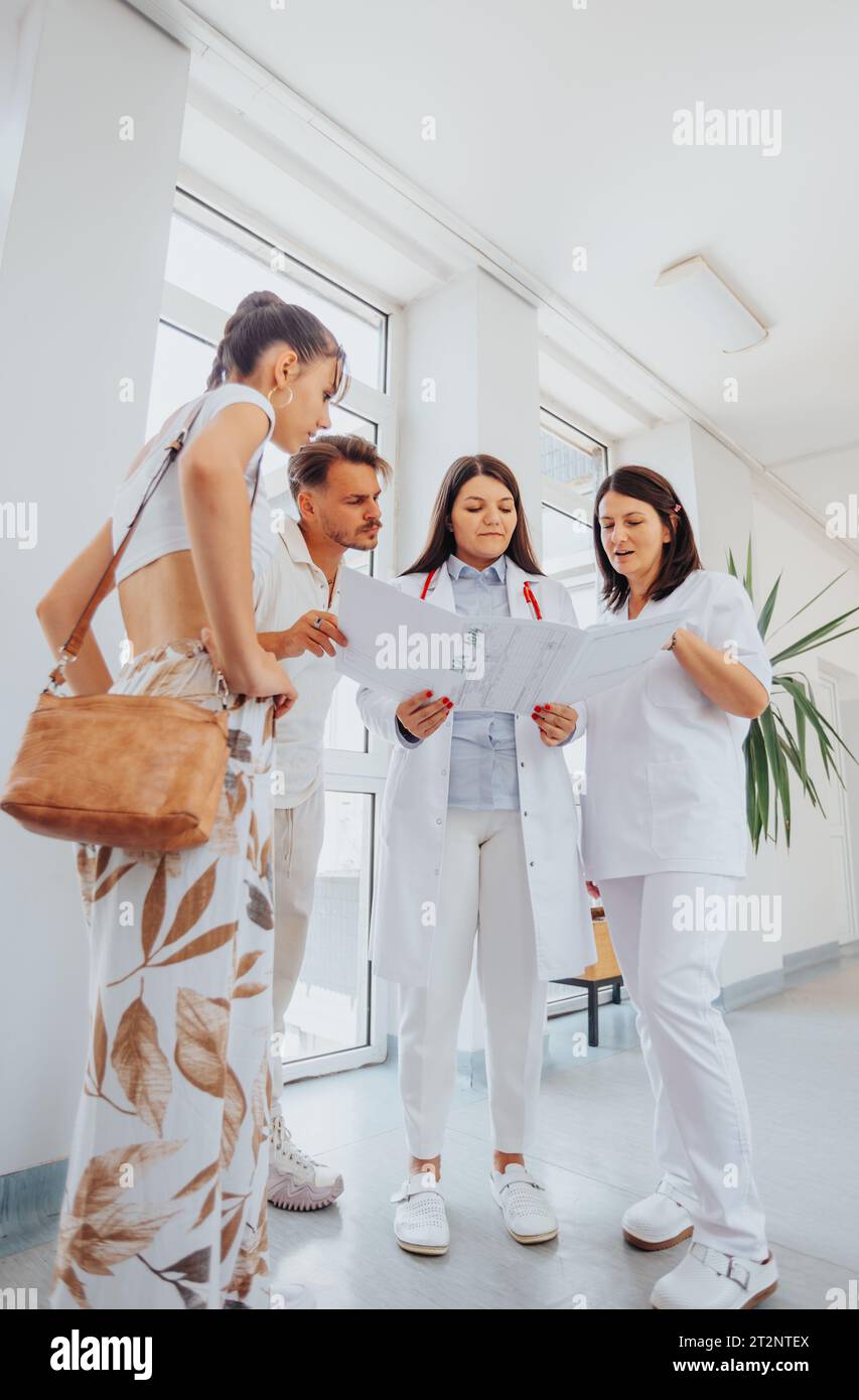 Group of doctors advising a smiling couple in a clinic, discussing ...