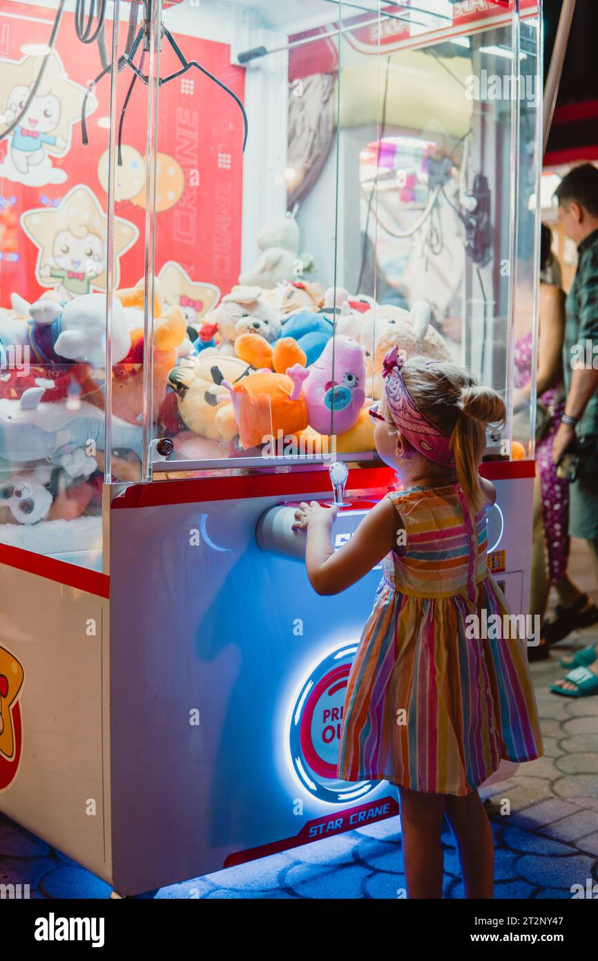 Little girl playing on a claw machine Stock Photo - Alamy