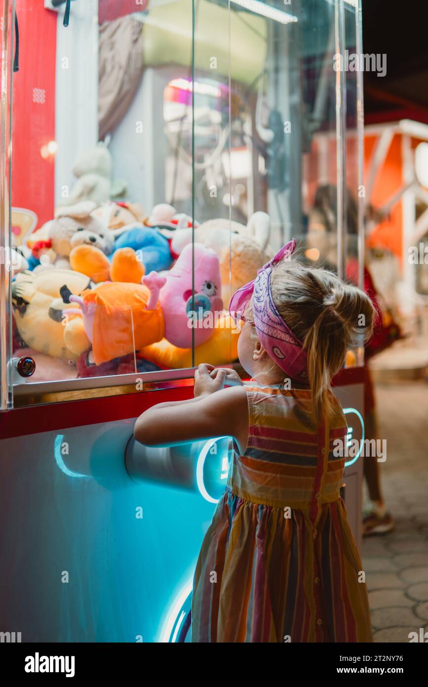 Little girl playing on a claw machine Stock Photo - Alamy