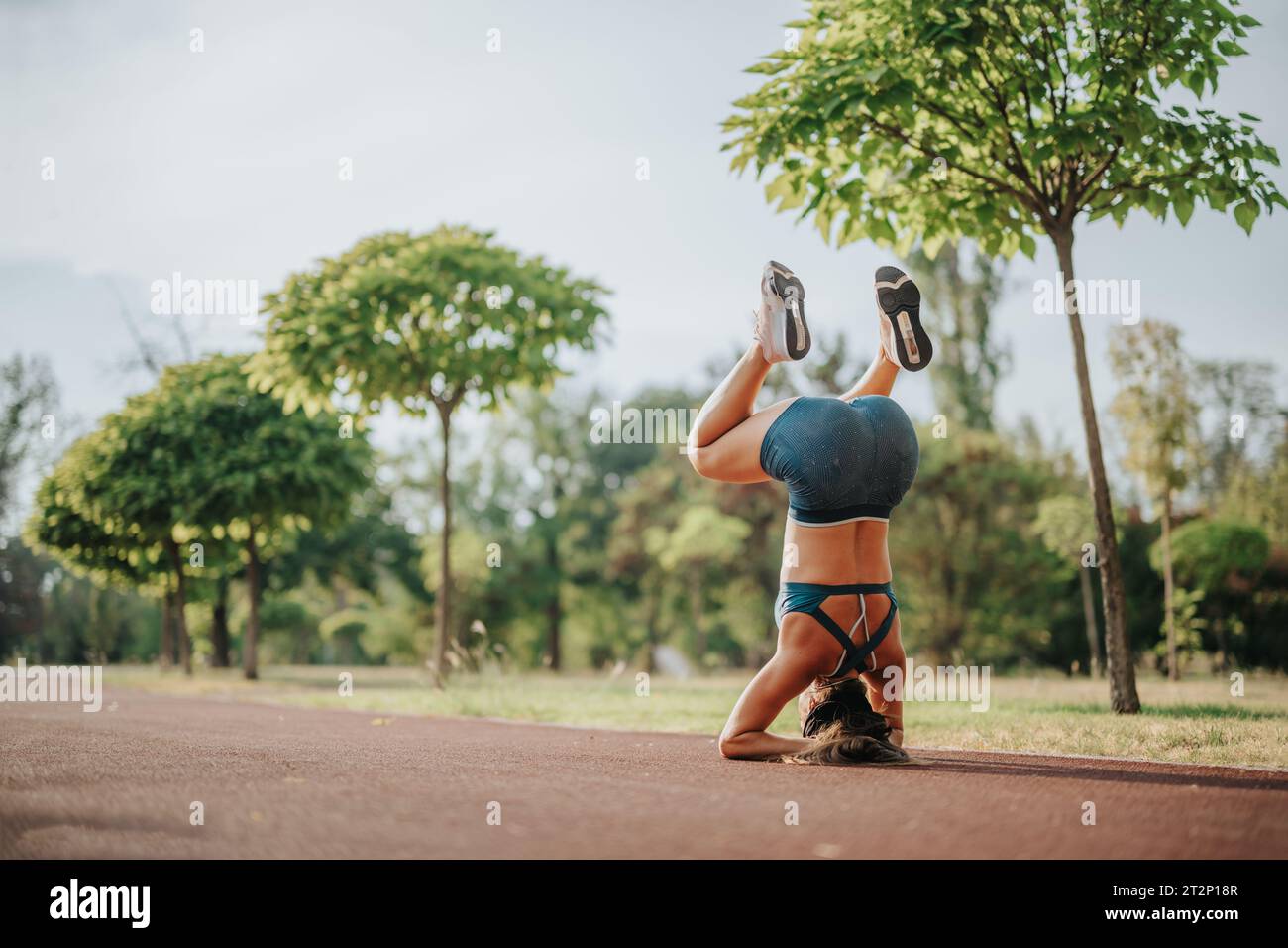 A fit girl displays strength and flexibility in a headstand pose amidst ...