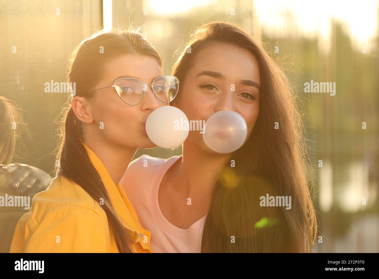 Beautiful young women blowing bubble gums outdoors on sunny day Stock ...